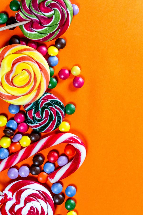 Фото: Разноцветные конфеты на оранжевом фоне